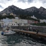 View of the port of Capri with colorful buildings and mountains in the background