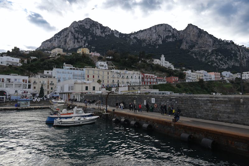 View of the port of Capri with colorful buildings and mountains in the background