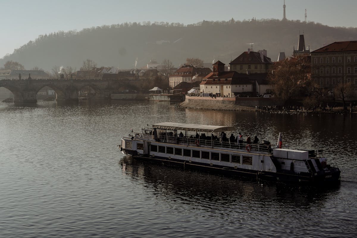 A boat on the Vltava River with Charles Bridge and historic Prague architecture in the background