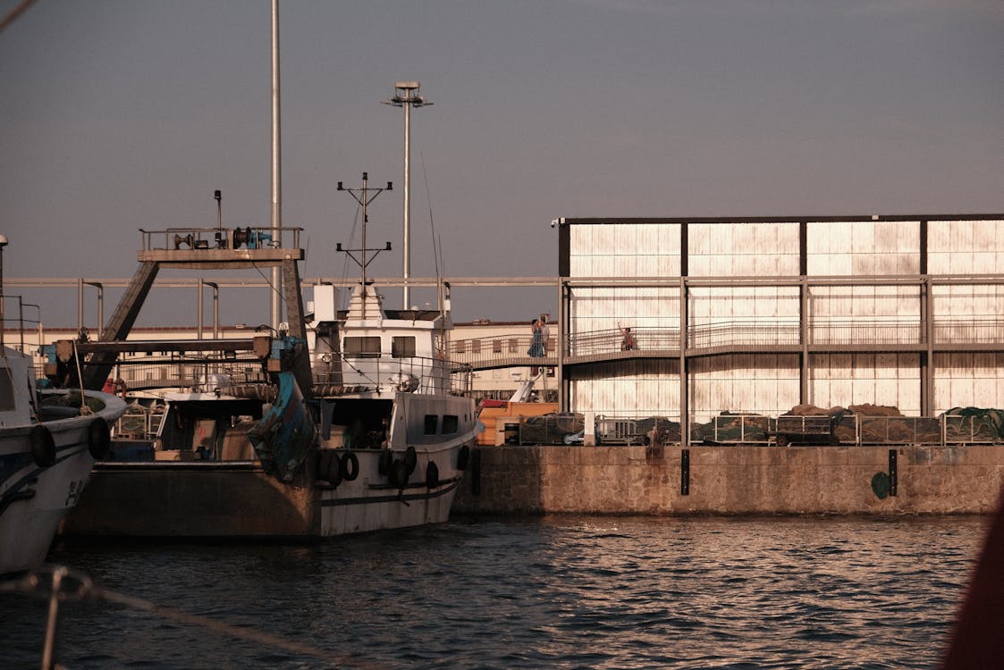 Fishing boats docked at Barcelona harbor with sunset glow over the water