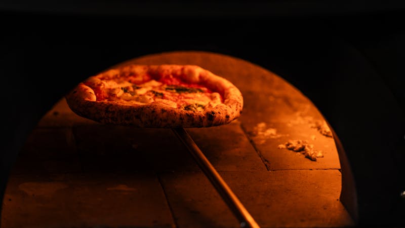 Neapolitan pizza baking inside a traditional wood-fired brick oven