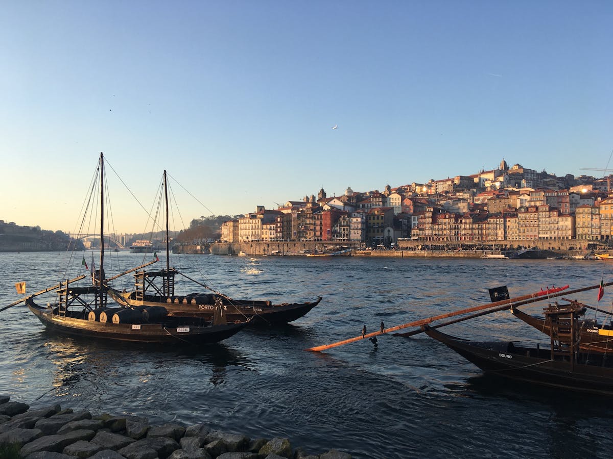 Traditional boats moored along the Porto riverfront bathed in warm golden evening light