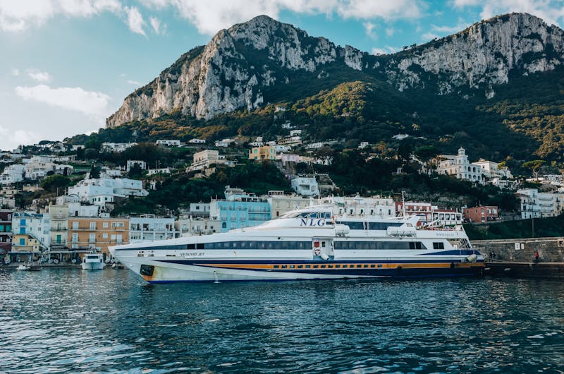 A ferry docked at Capri Island harbor with mountain and town view