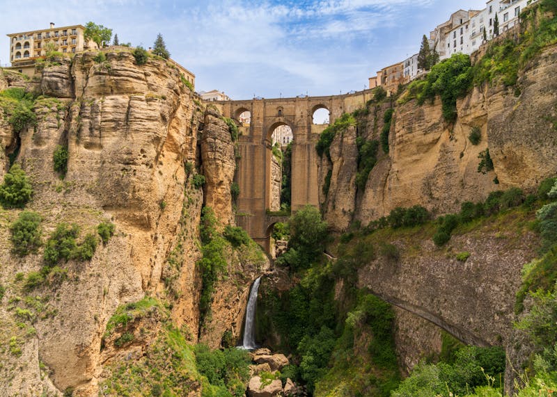 Puente Nuevo bridge over El Tajo gorge with lush green vegetation on the cliff sides