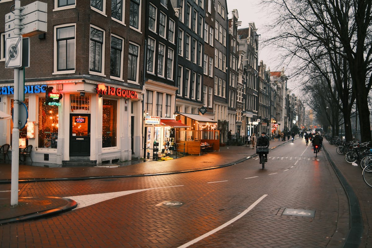 Cyclists riding through Amsterdam at dusk with Dutch architecture in the background