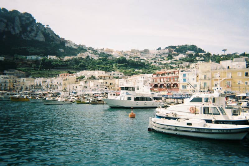 Boats docked at Marina Grande harbor with scenic hills in Capri Italy