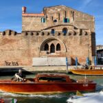 Classic water taxis cruising through historic Venice canals with brick buildings