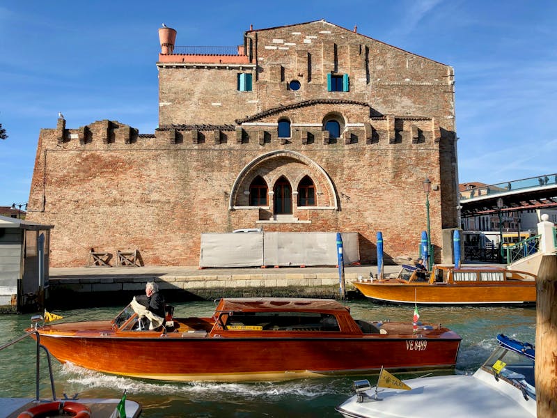 Classic water taxis cruising through historic Venice canals with brick buildings