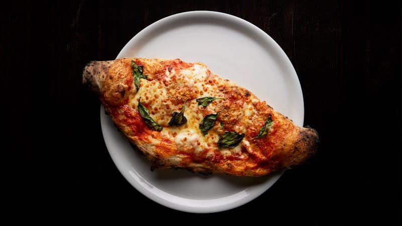 Close-up of a freshly baked Neapolitan calzone with mozzarella and basil