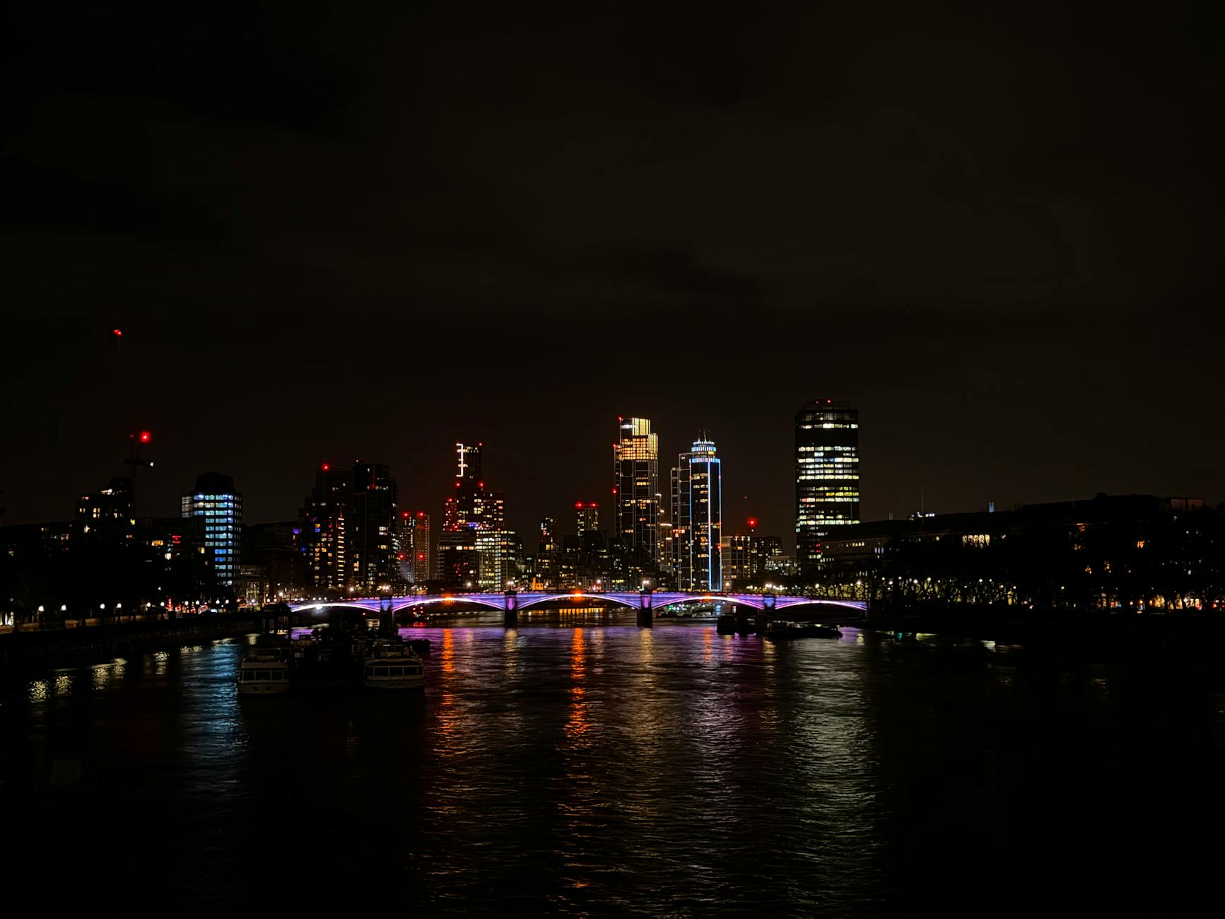 London skyline at night showing illuminated skyscrapers and a river view
