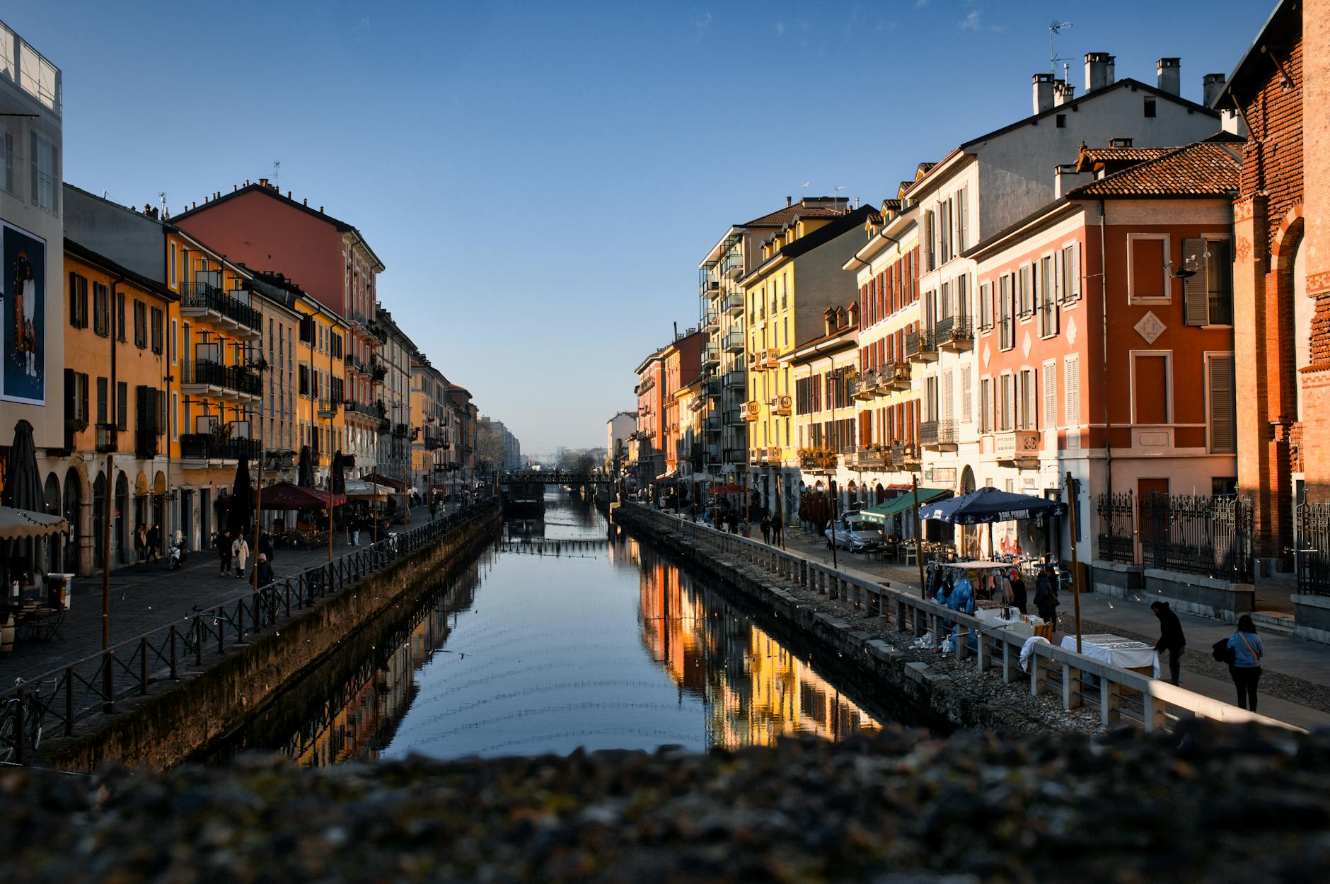 Colorful buildings and outdoor cafes lining a canal in the Navigli district of Milan