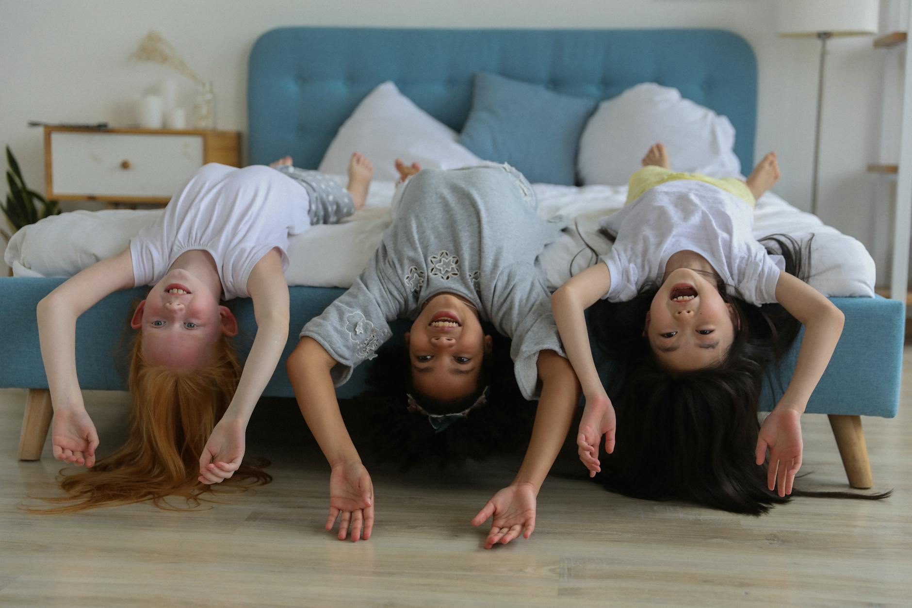 Cheerful multiracial children lying on a bed laughing and playing together