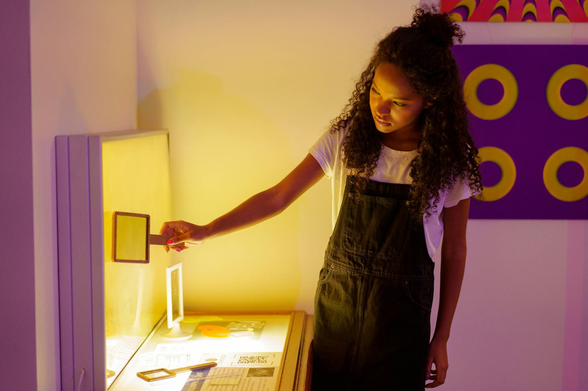 A teenager with curly hair exploring an interactive art exhibit with purple and blue lighting