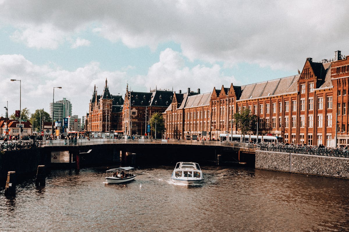 A canal in Amsterdam with a passing boat and traditional Dutch buildings on both sides