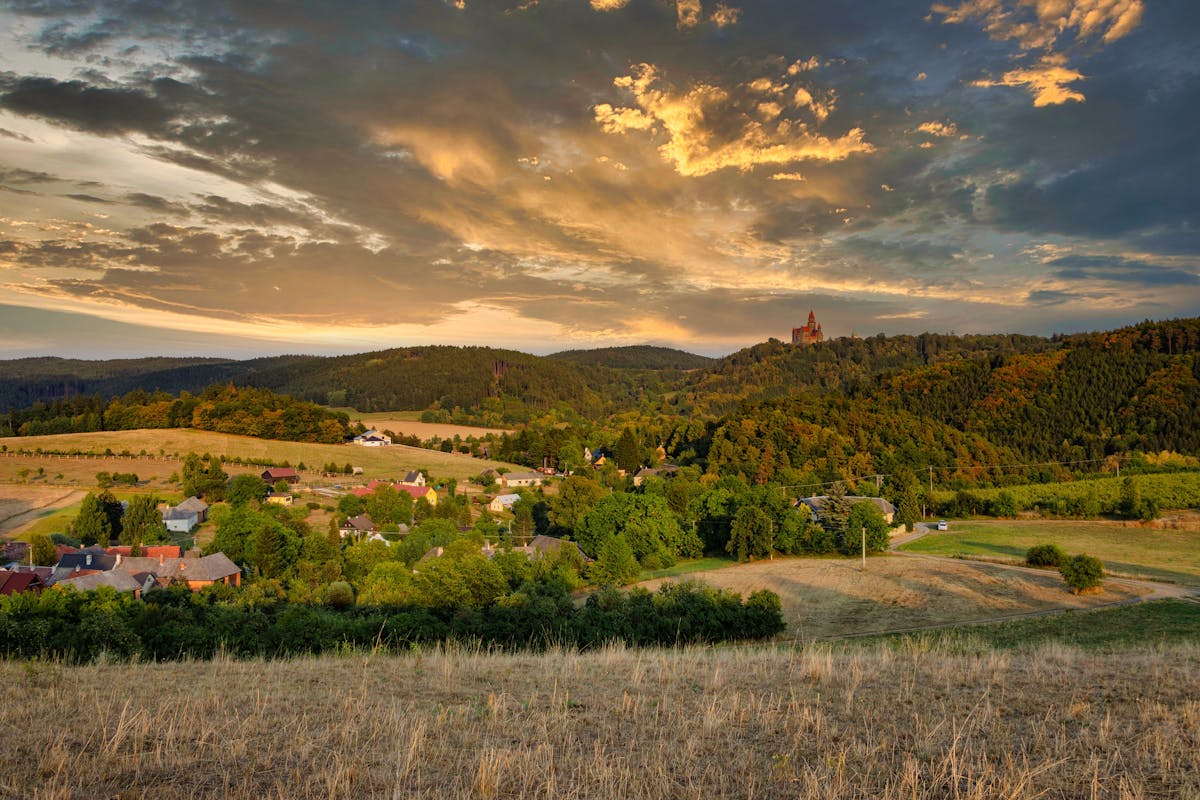 Scenic view of a Czech village surrounded by green hills at sunset