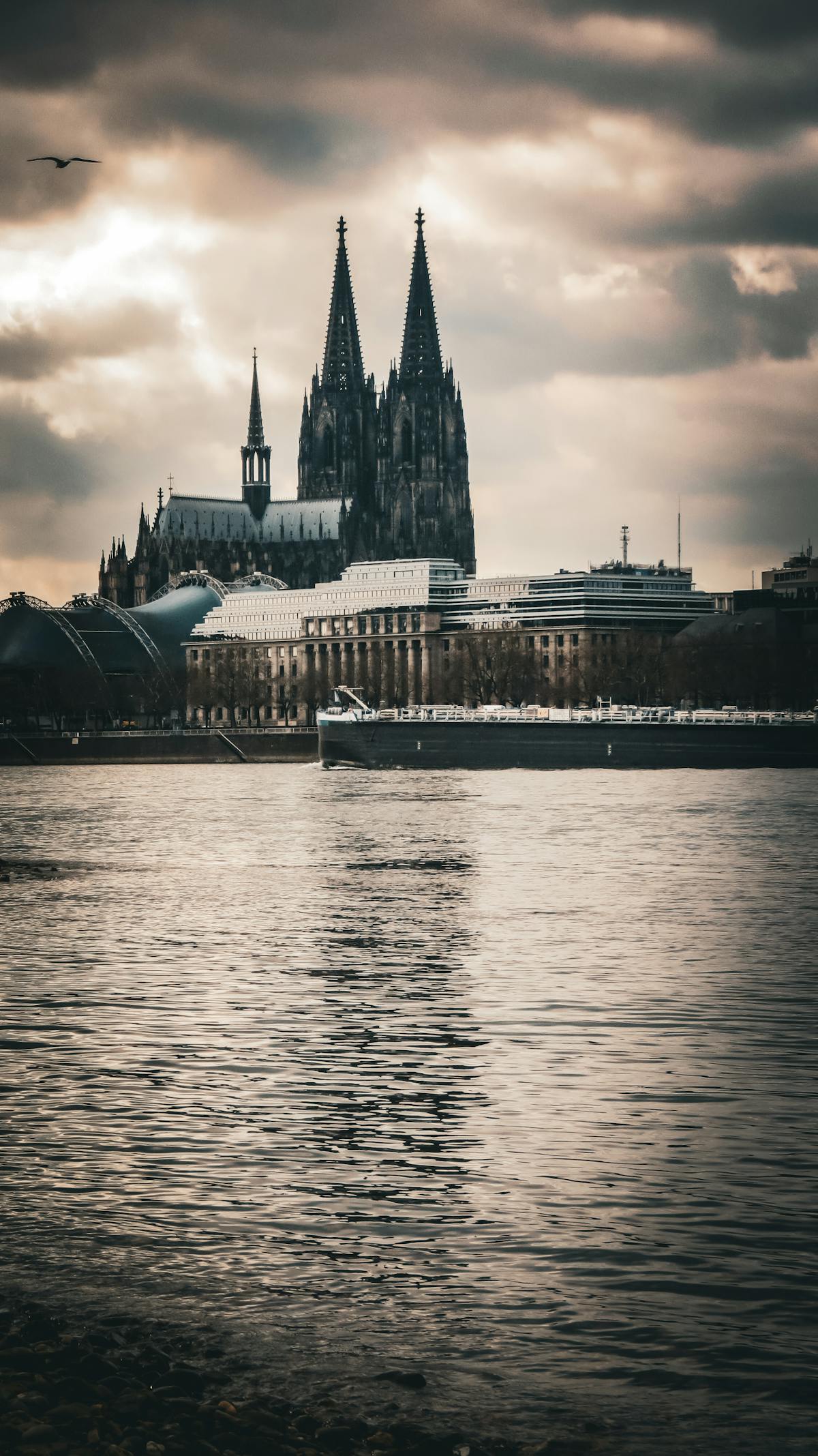Cologne Cathedral spires rising against dramatic sky beside the Rhine River