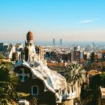 Aerial view of Park Guell showing colorful mosaic terraces and Barcelona cityscape