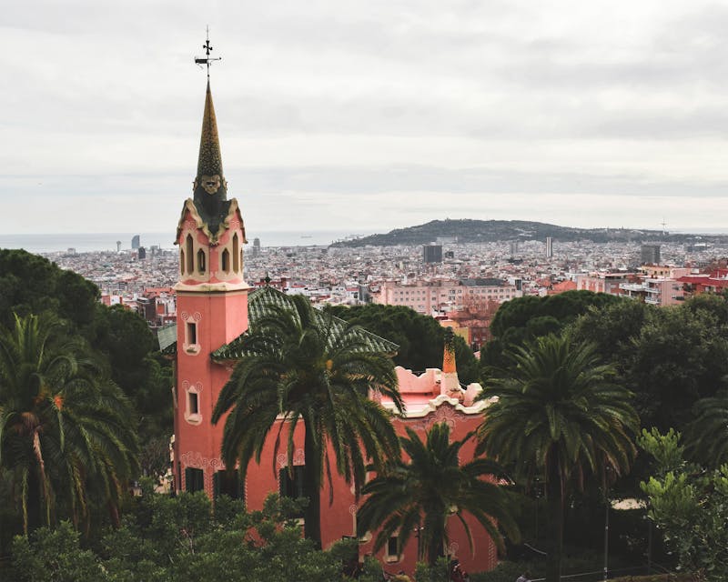 The pink spire of the Gaudi House Museum at Park Guell with Barcelona skyline behind