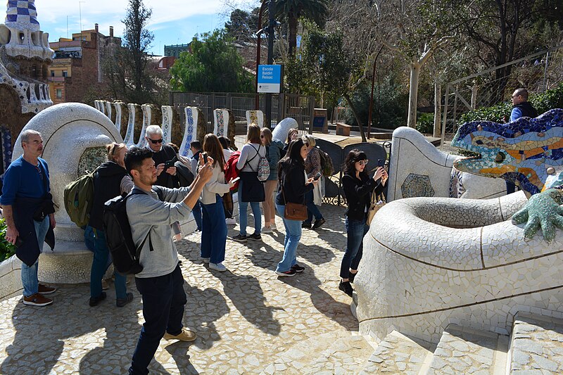 Main entrance staircase of Park Guell with mosaic decorations and visitors