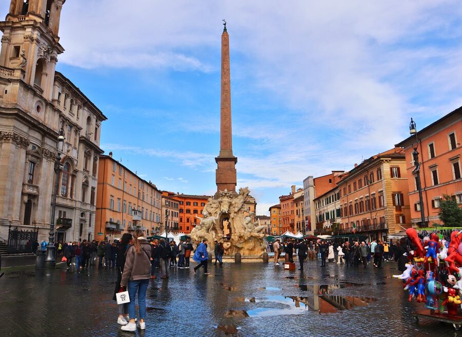 Busy Piazza Navona with travelers and the iconic Fountain of the Four Rivers in Rome