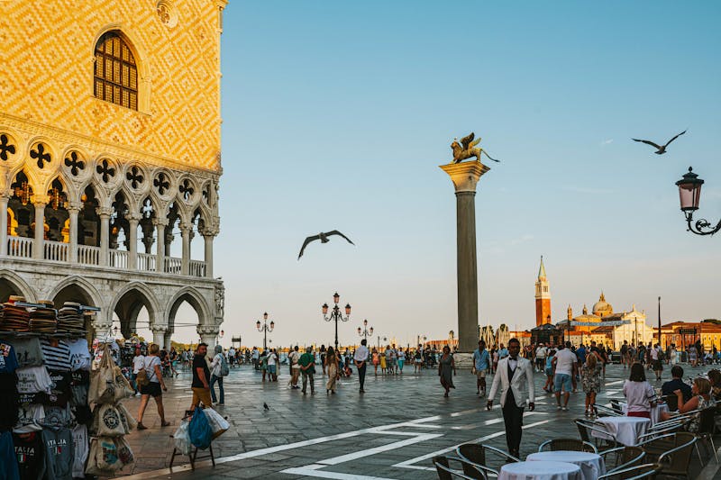 Piazza San Marco at sunset with visitors walking near the Palazzo Ducale and St Marks Campanile
