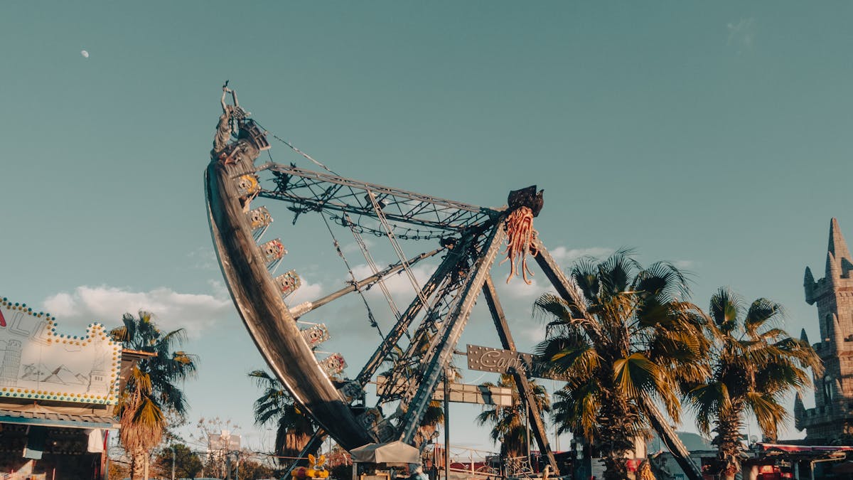 Dramatic pirate ship ride amidst palm trees at sunset in an amusement park