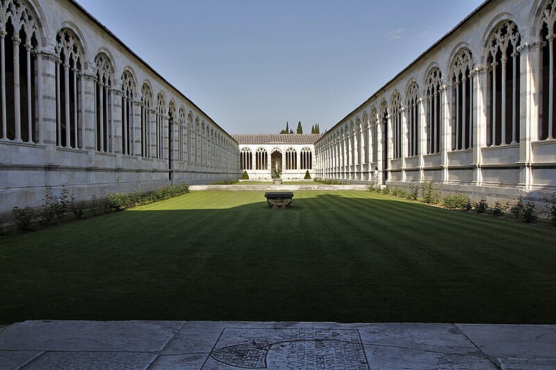 The peaceful interior courtyard of Camposanto Monumentale with arched colonnades and green lawn
