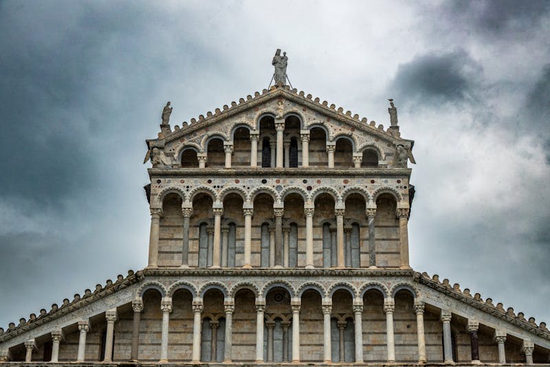 Close-up of Pisa Cathedral Romanesque facade with dramatic clouds