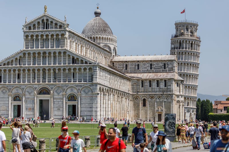 Crowds of visitors exploring Pisa Cathedral and the Leaning Tower in Piazza dei Miracoli