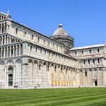 The Leaning Tower of Pisa and Pisa Cathedral under blue skies in Piazza dei Miracoli