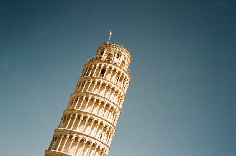 Low angle view of the Leaning Tower of Pisa with its white marble tiers against blue sky