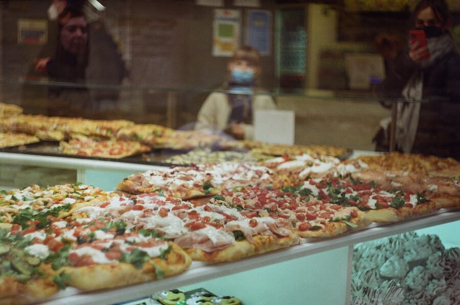 Assorted pizzas displayed in a bakery showcase