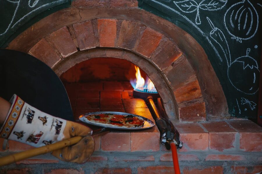 A pizza baking in a traditional wood-fired brick oven at an Italian cooking class