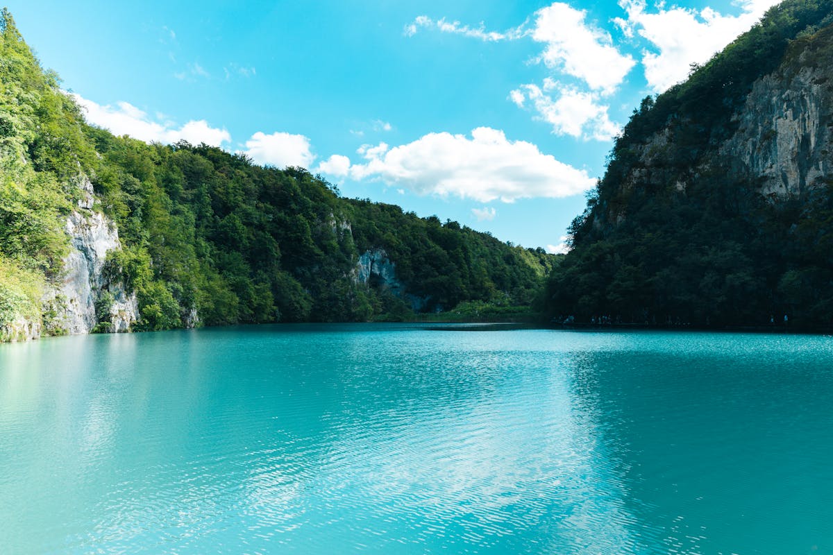 Turquoise waters surrounded by greenery and cliffs at Plitvice Lakes National Park Croatia