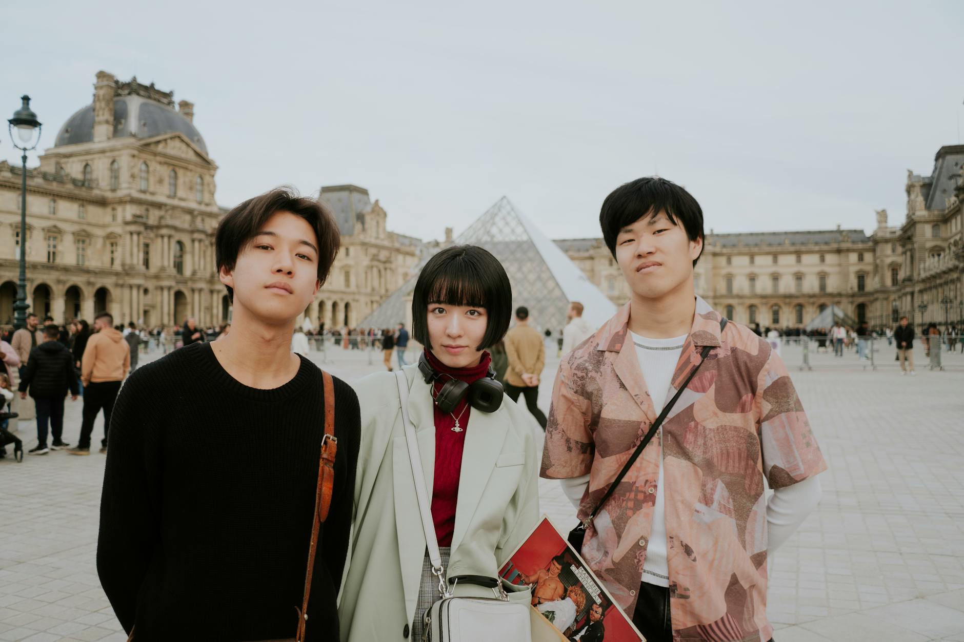 Tourists posing in front of the Louvre Pyramid in Paris