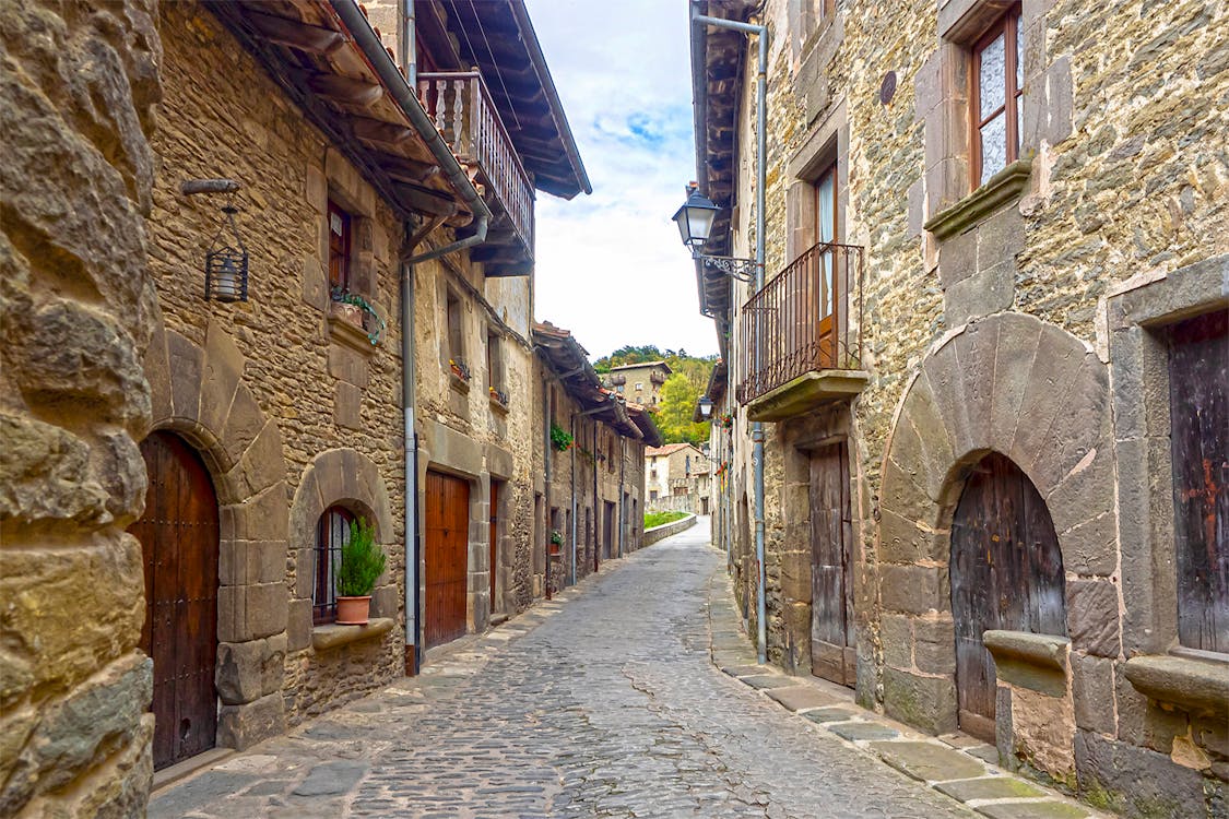 Historic stone buildings with hanging plants on a narrow village street