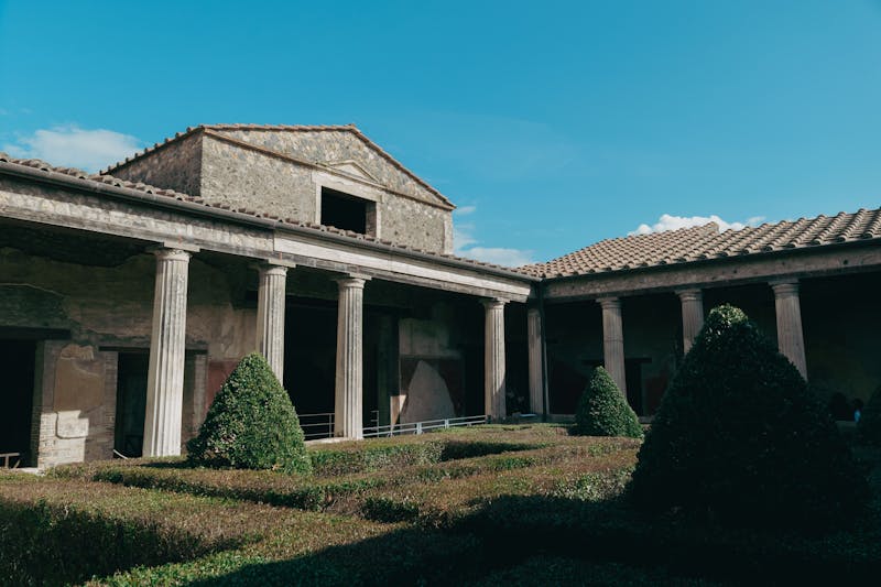 Well-preserved ruins of a Roman courtyard with columns and stone walls in Pompeii under clear blue sky