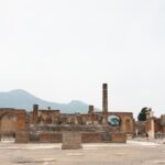 Ancient ruins of Pompeii with Mount Vesuvius visible in the background under blue sky