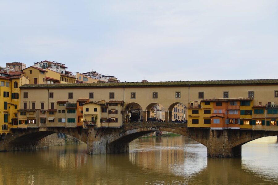 Historic Ponte Vecchio bridge in Florence illuminated at dusk with calm Arno River
