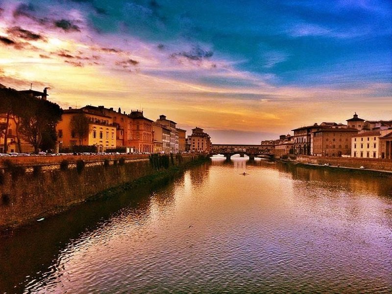 Ponte Vecchio bridge in Florence at sunset with golden light reflecting on the Arno River