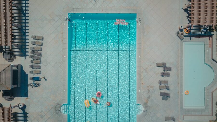 Aerial view of a lively pool with floats and people enjoying the sun
