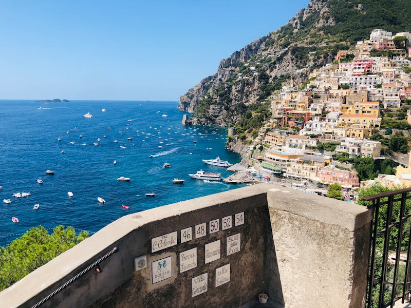 View from a balcony overlooking Positano town and boats sailing on the Amalfi Coast