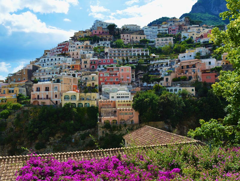 Vibrant houses built along the cliffside in Positano surrounded by lush greenery