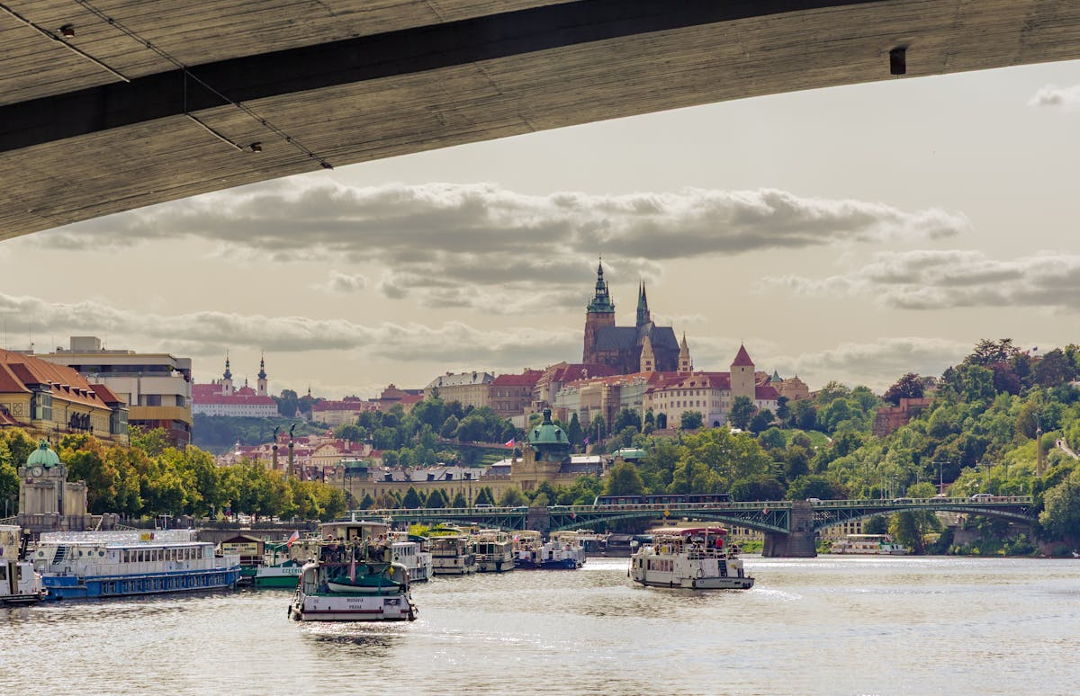 Prague Castle seen from the Vltava River with sightseeing boats near a bridge