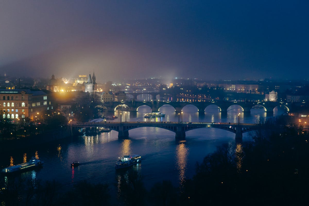 Illuminated bridges spanning the Vltava River in Prague at night with city lights