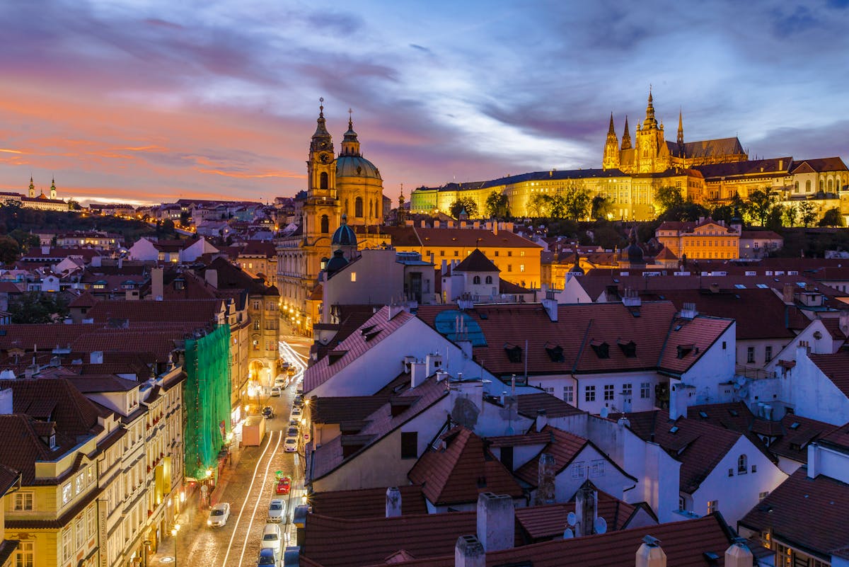 Stunning night view of Prague illuminated cityscape featuring rooftops and a church