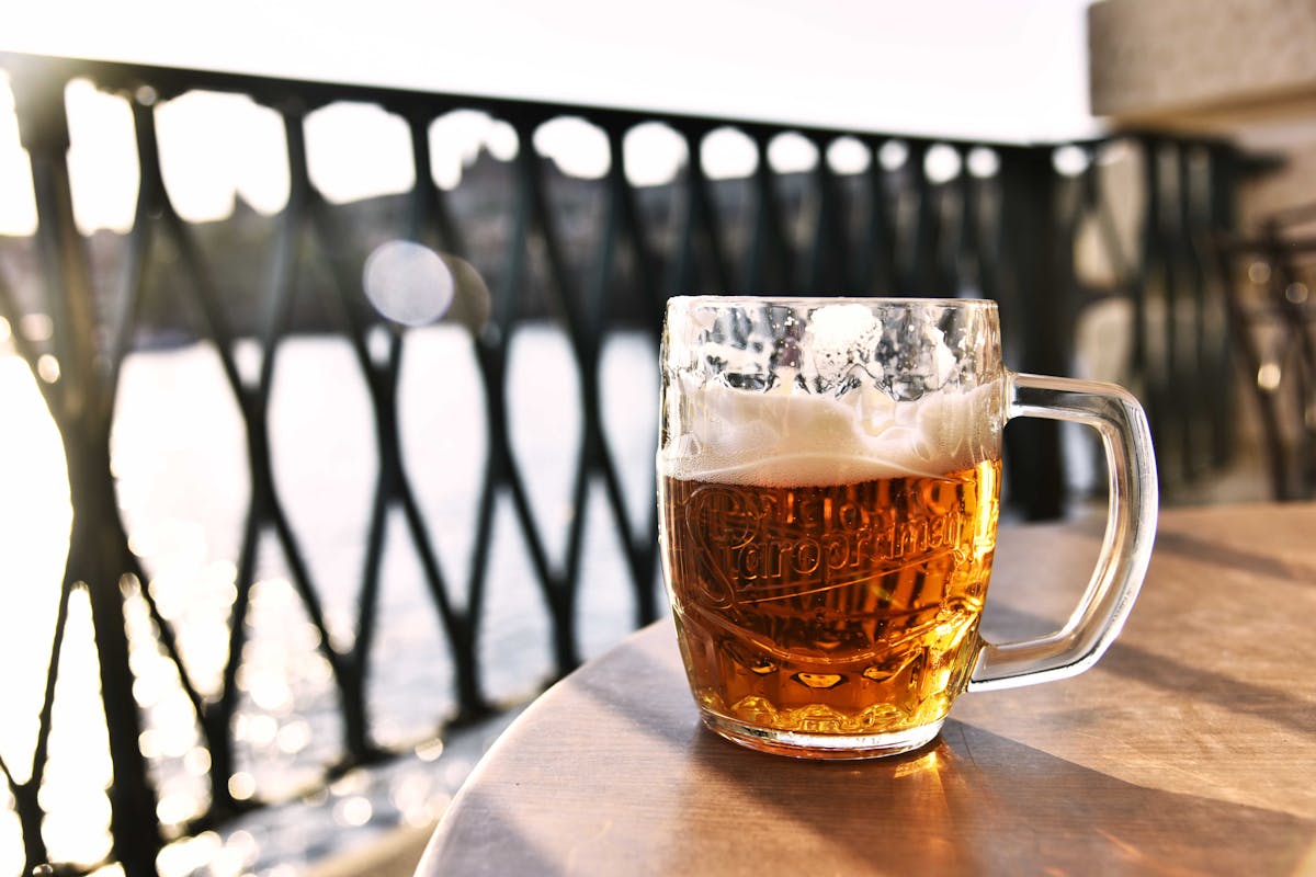 Refreshing lager beer mug with scenic Prague river view in background