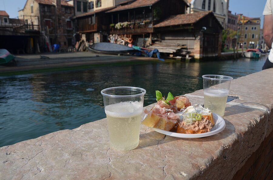 A glass of prosecco alongside cicchetti small plates at a Venetian wine bar