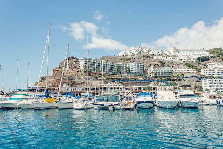Marina with yachts and sailboats against a hillside backdrop