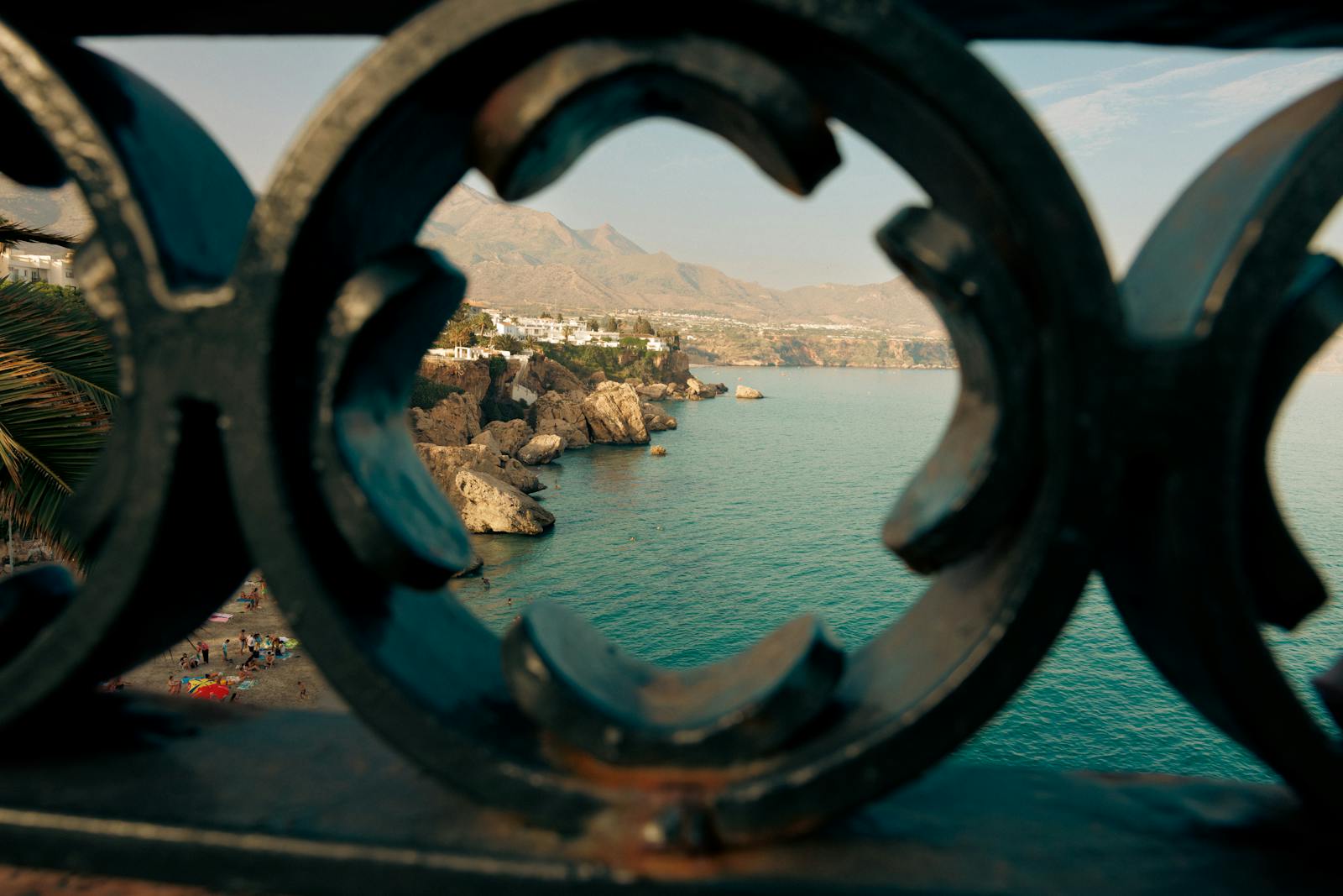 Ocean view framed by artistic ironwork railing with distant cliffs